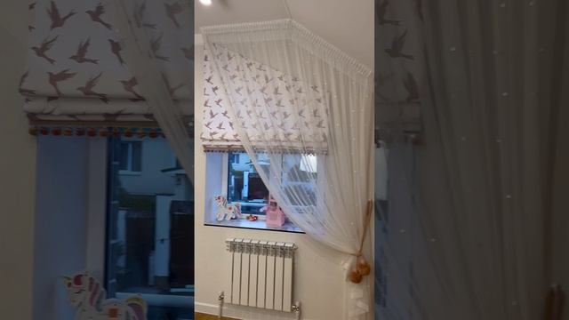 Римские шторы с помпонами и тюль на скошенные окна в детскую