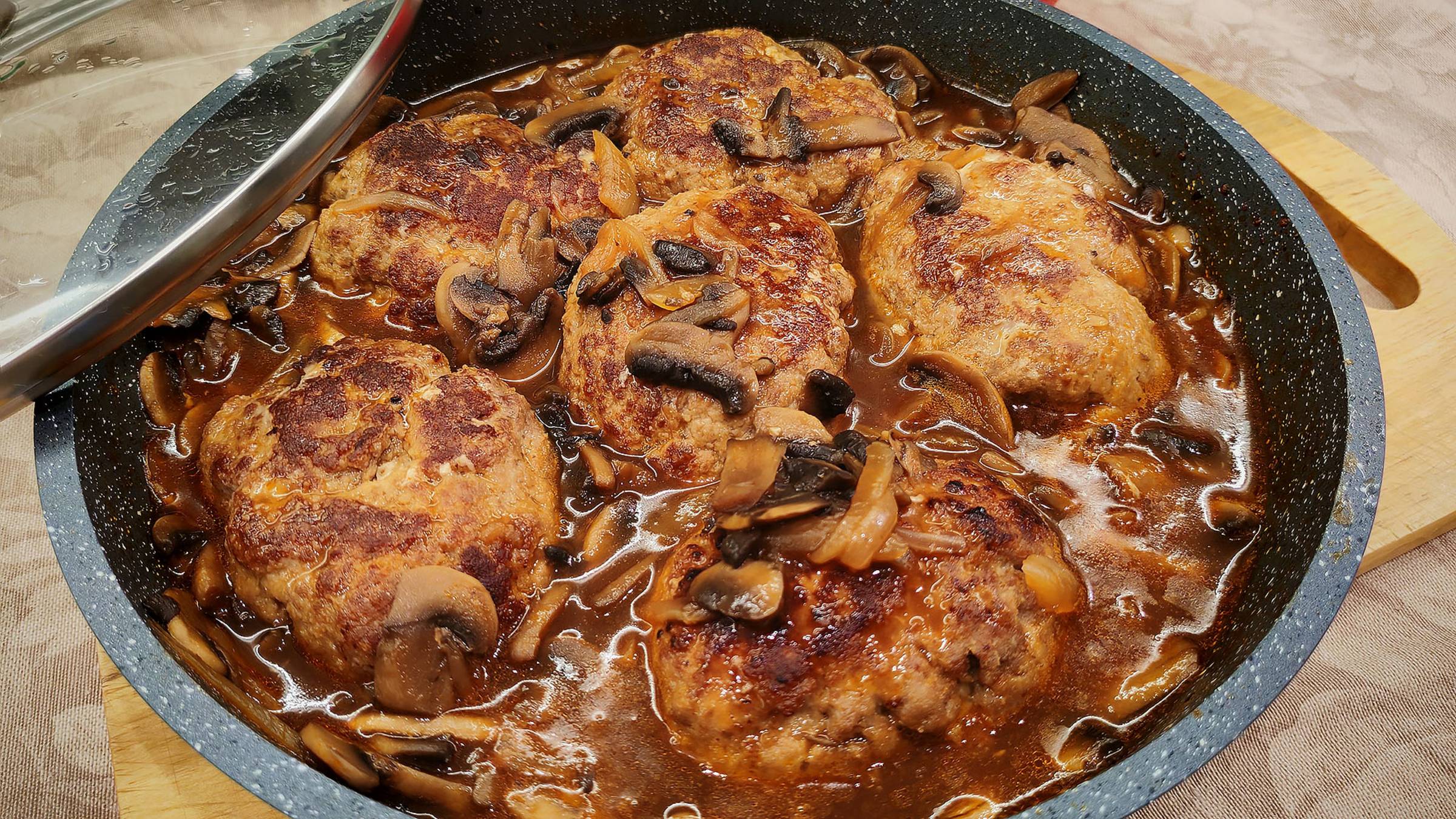 Говяжьи котлеты с грибным соусом на сковороде.