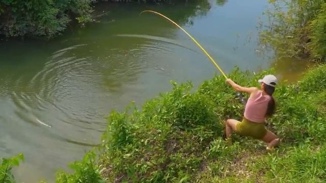 Девушка с крючком ловит гигантского черного карпа