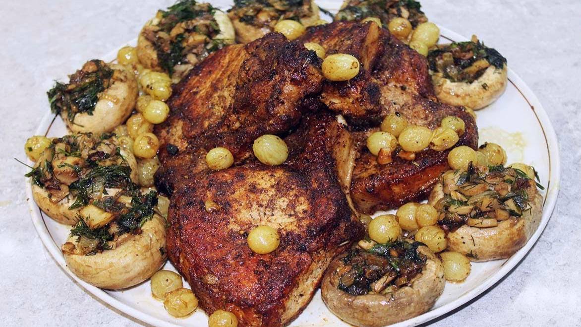 Свиная корейка на кости в казане с шампиньонами и виноградом.