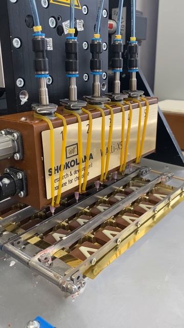 Станок WALLi-X5 наносит символы на плитки шоколада.