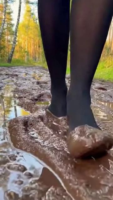 Девушка в чёрных колготках ходит по грязной дороге