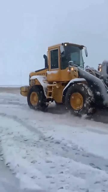 Колесный погрузчик Volvo L90E скользит по ледяной дороге с включенными тормозами