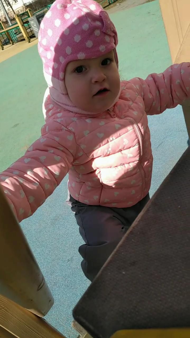 Арина на детской площадке пытается забраться на горку и играет с тенью