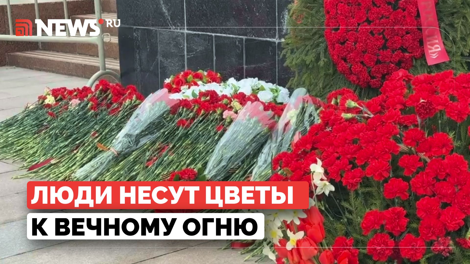 Люди 9 мая несут цветы к Вечному огню на Поклонной горе