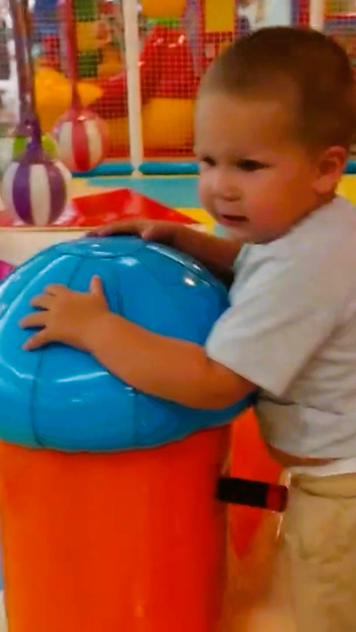 Ребенок играет на детской площадке,  катается на карусели и скатывается с горки