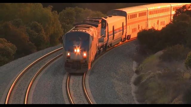 Американский тепловоз везет очень красивые двухэтажные пассажирские поезда через небольшой город