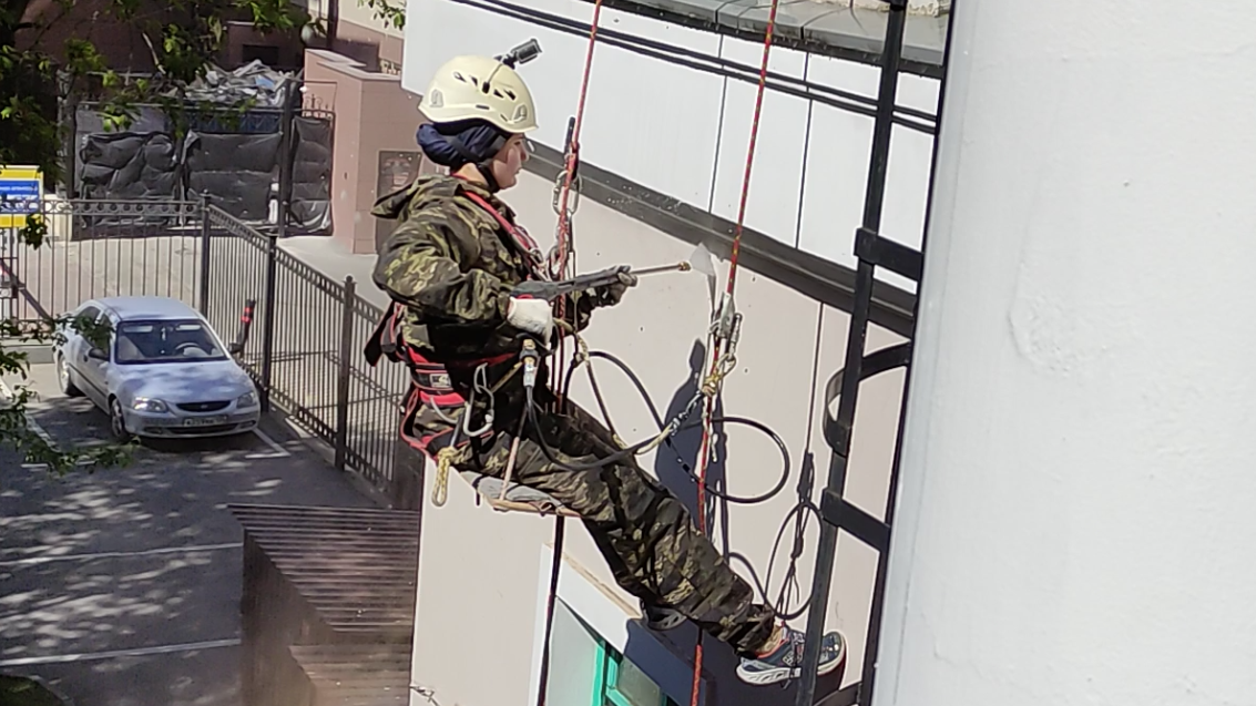 Съёмка экшн-камерой подъёма на верх промышленного альпиниста, спуск вниз на канатах для мойки фасада