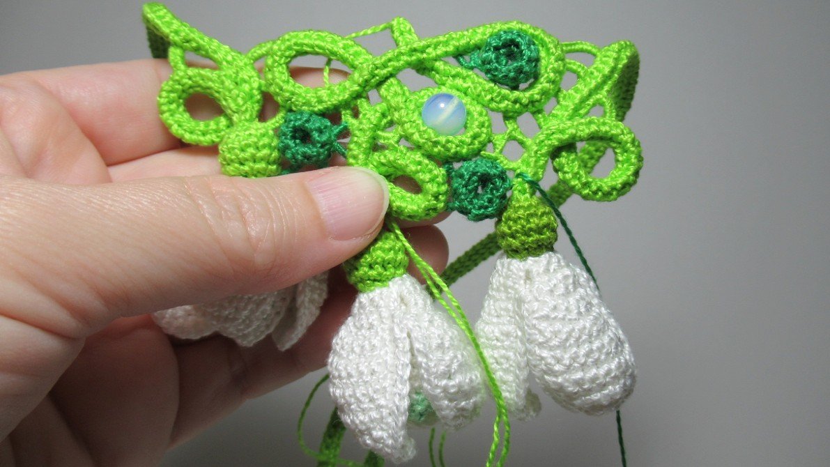 Прикрепляю вязаный цветок подснежника к третьему колечку в вязаном крючком колье