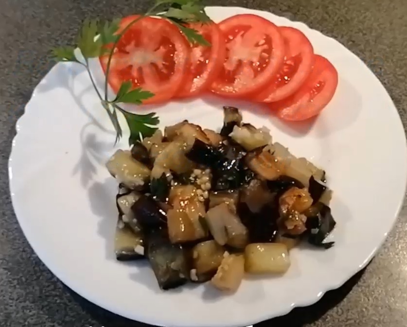 Баклажаны жареные кубиком на сковороде с чесноком.