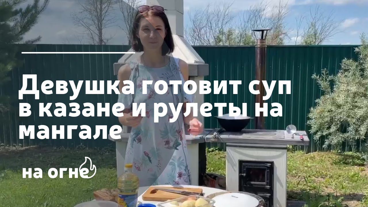 Девушка готовит гороховый суп и куриные рулетики на огне в казане