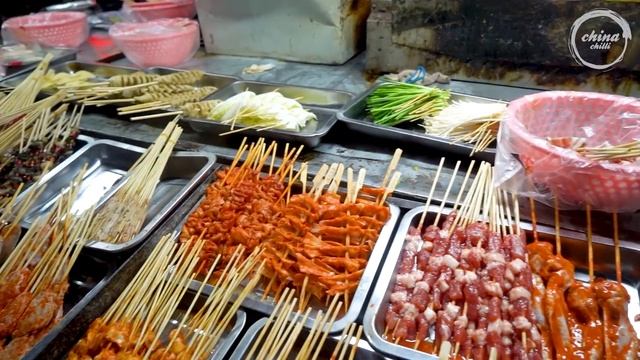 Chinese Street Food -Fried noodles with egg and fried rice at night market, skewers at food stalls