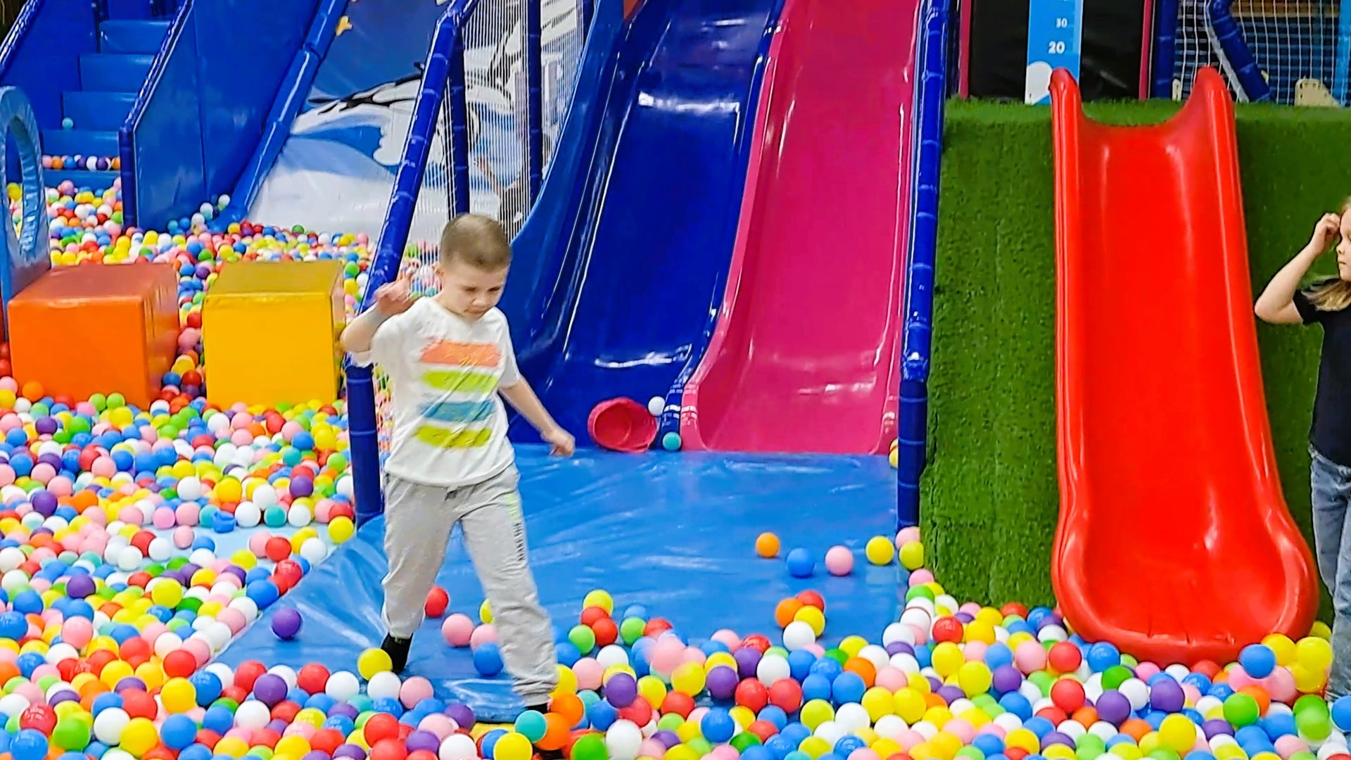 Ребенок катается с горки на детской площадке и прыгает набатуте